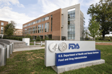 A modern brick and glass building with a sign in front reading "U.S. Department of Health and Human Services, Food and Drug Administration (FDA)" on a landscaped campus.