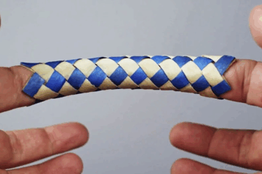 Two hands with index fingers inserted into a blue and beige woven Chinese finger trap against a plain background.